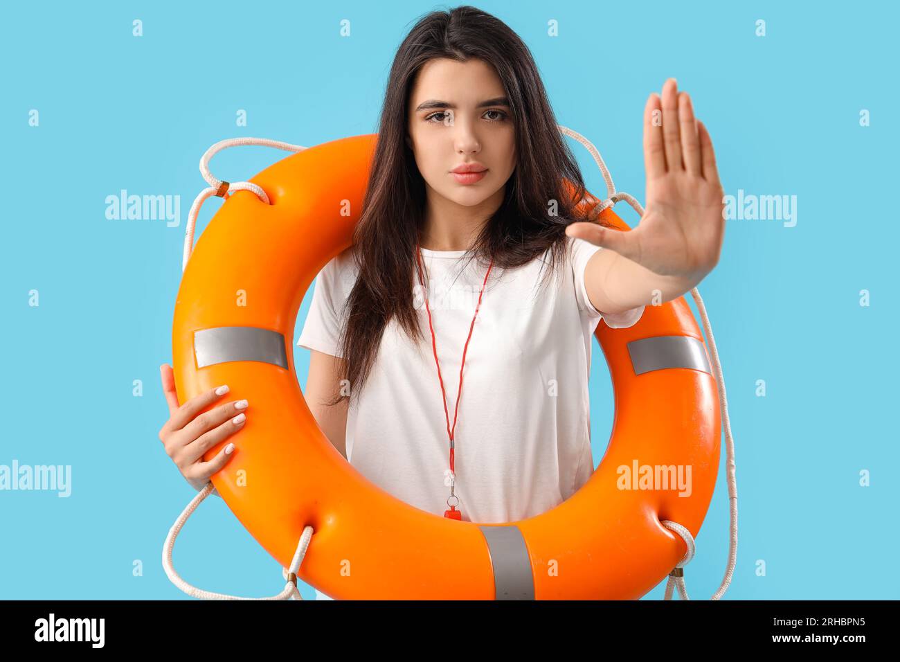 Female lifeguard with ring buoy showing stop gesture on blue background ...
