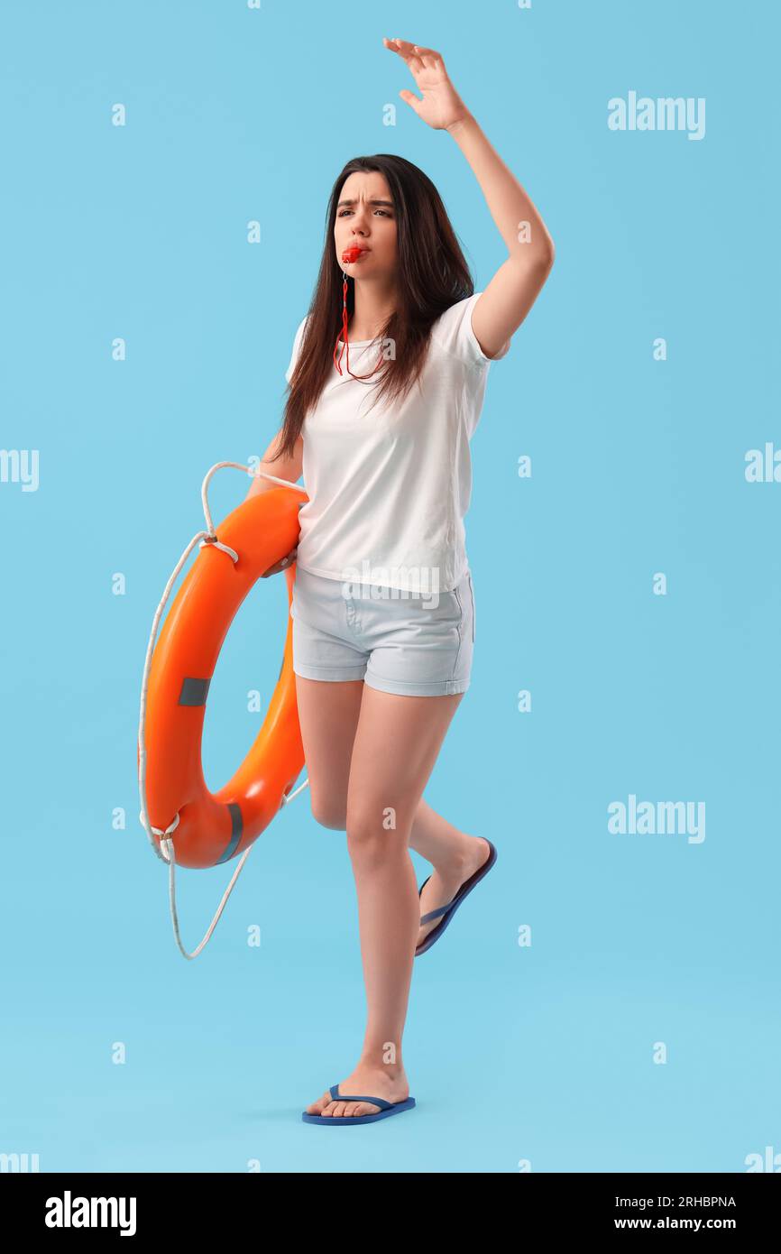 Female lifeguard with ring buoy whistling on blue background Stock ...
