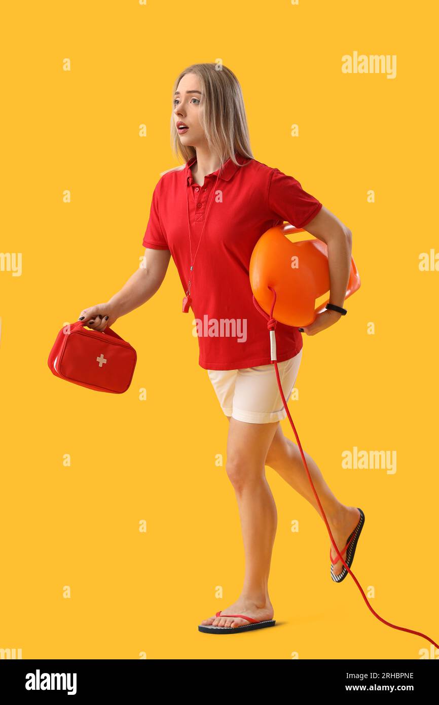Female lifeguard with rescue buoy and first aid kit on yellow ...