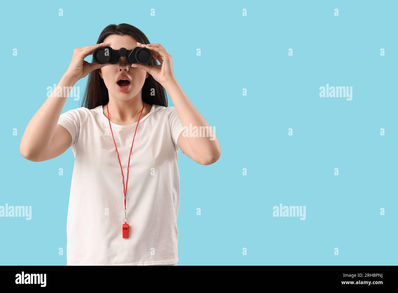 Shocked female lifeguard with binoculars on blue background Stock Photo ...