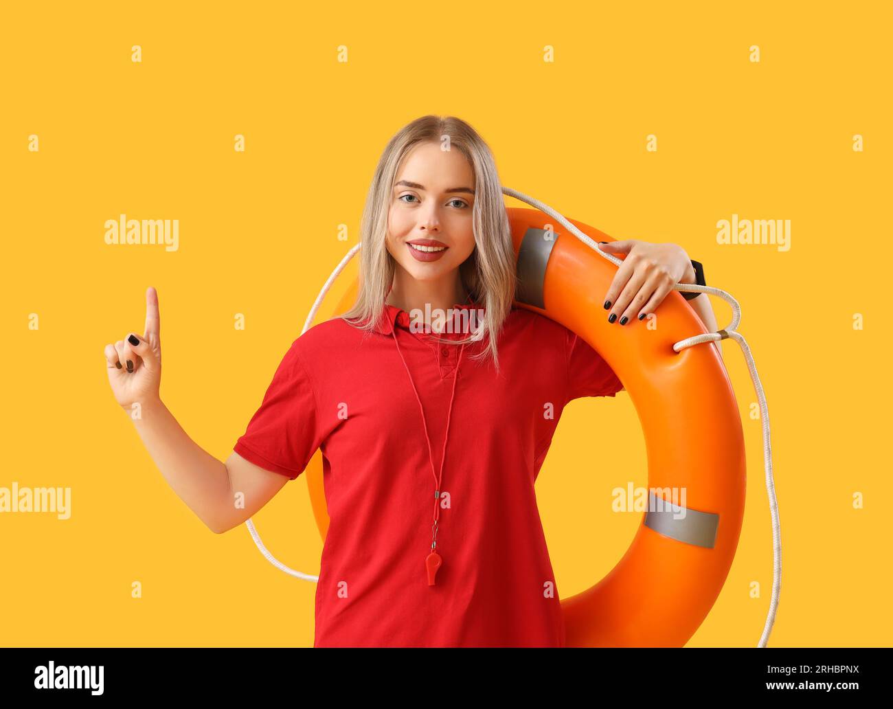 Female lifeguard with ring buoy pointing at something on yellow ...