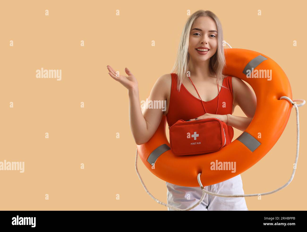Female lifeguard with ring buoy and first aid kit on beige background ...