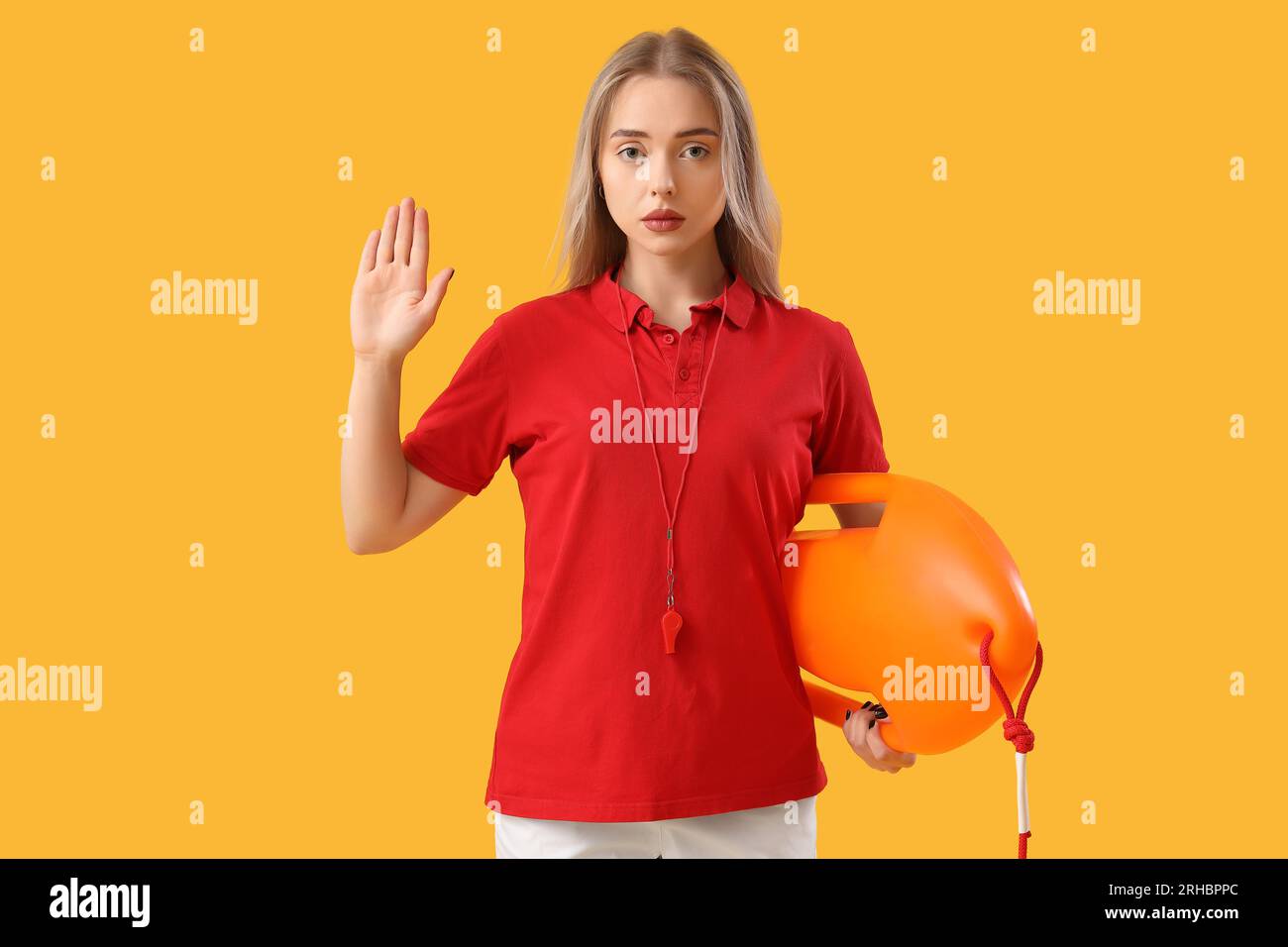Female lifeguard with rescue buoy showing stop gesture on yellow ...