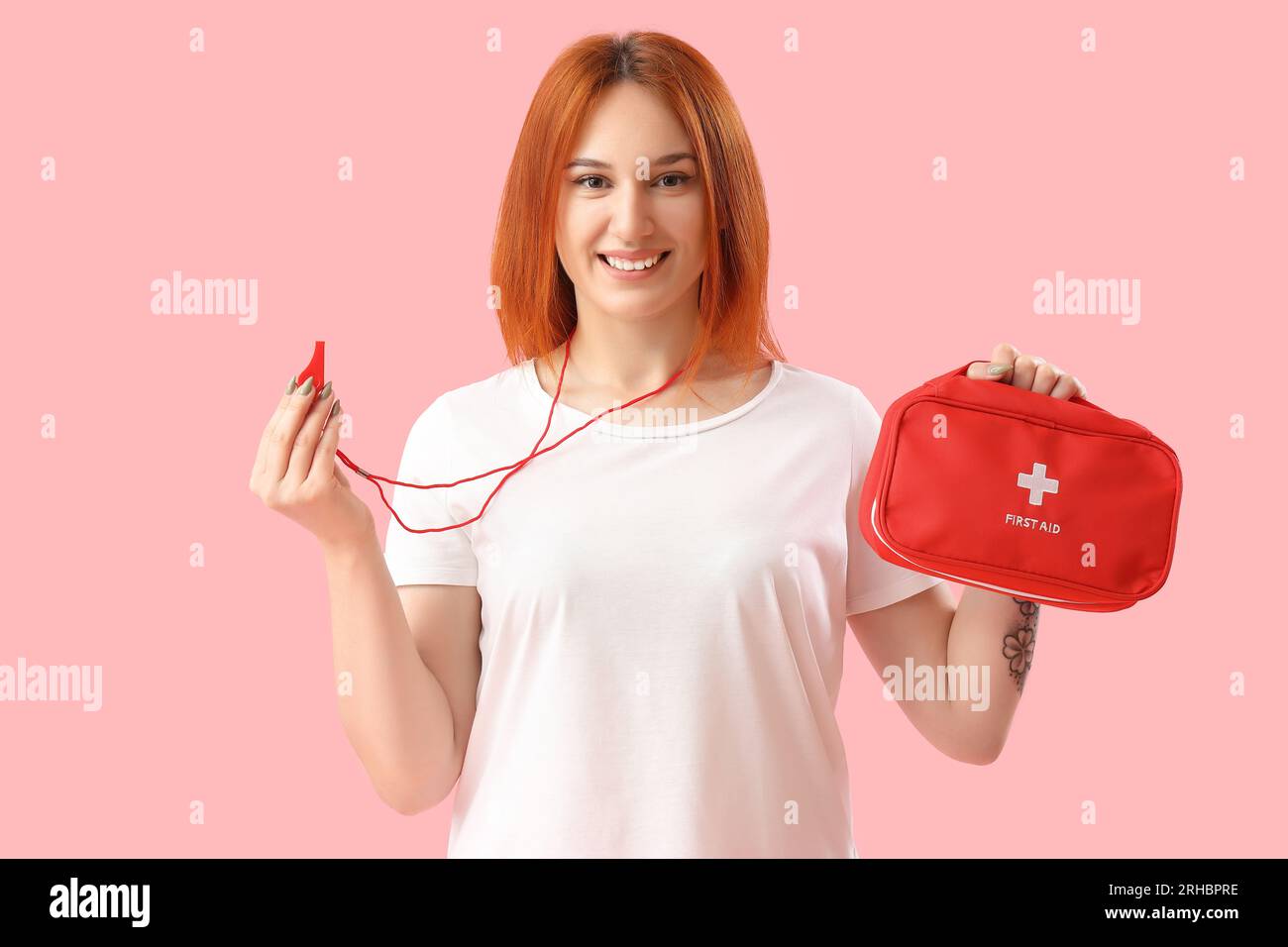 Female lifeguard with whistle and first aid kit on pink background ...
