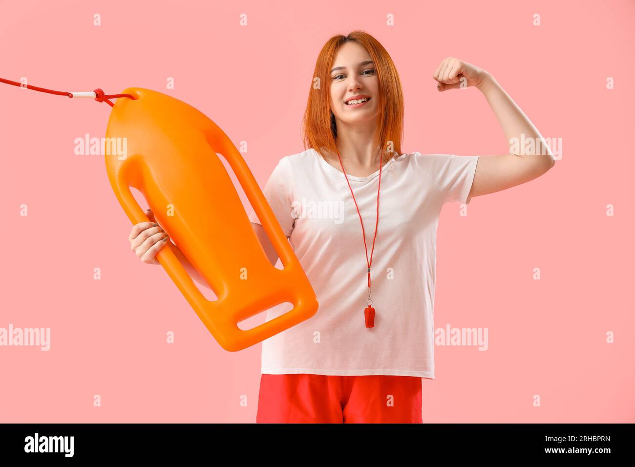 Female lifeguard with rescue buoy showing muscles on pink background ...