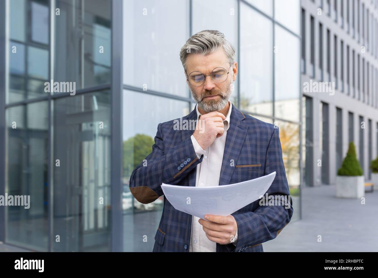 Thoughtful businessman reading documents outdoors hi-res stock ...