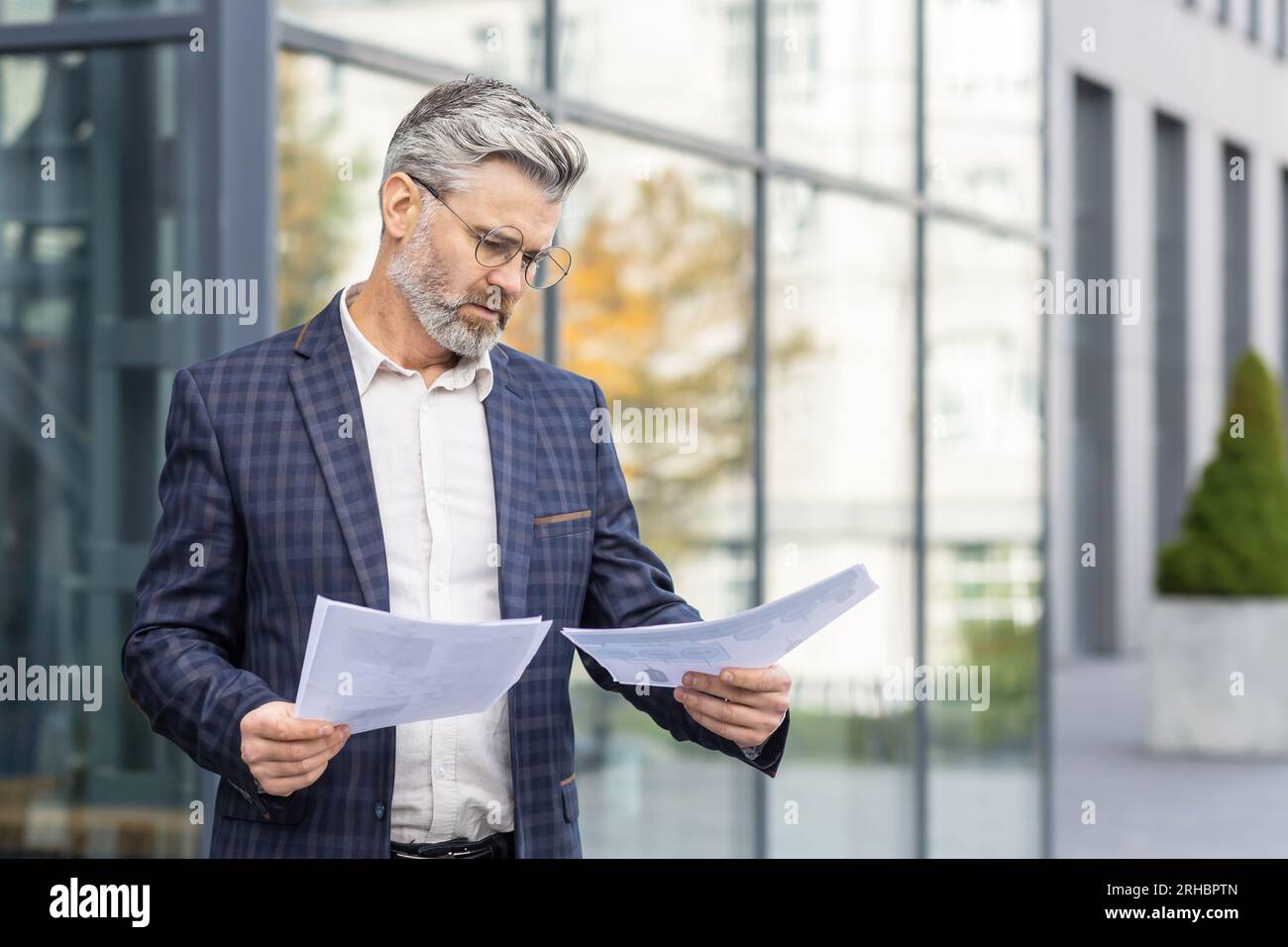 Thoughtful businessman reading documents outdoors hi-res stock ...