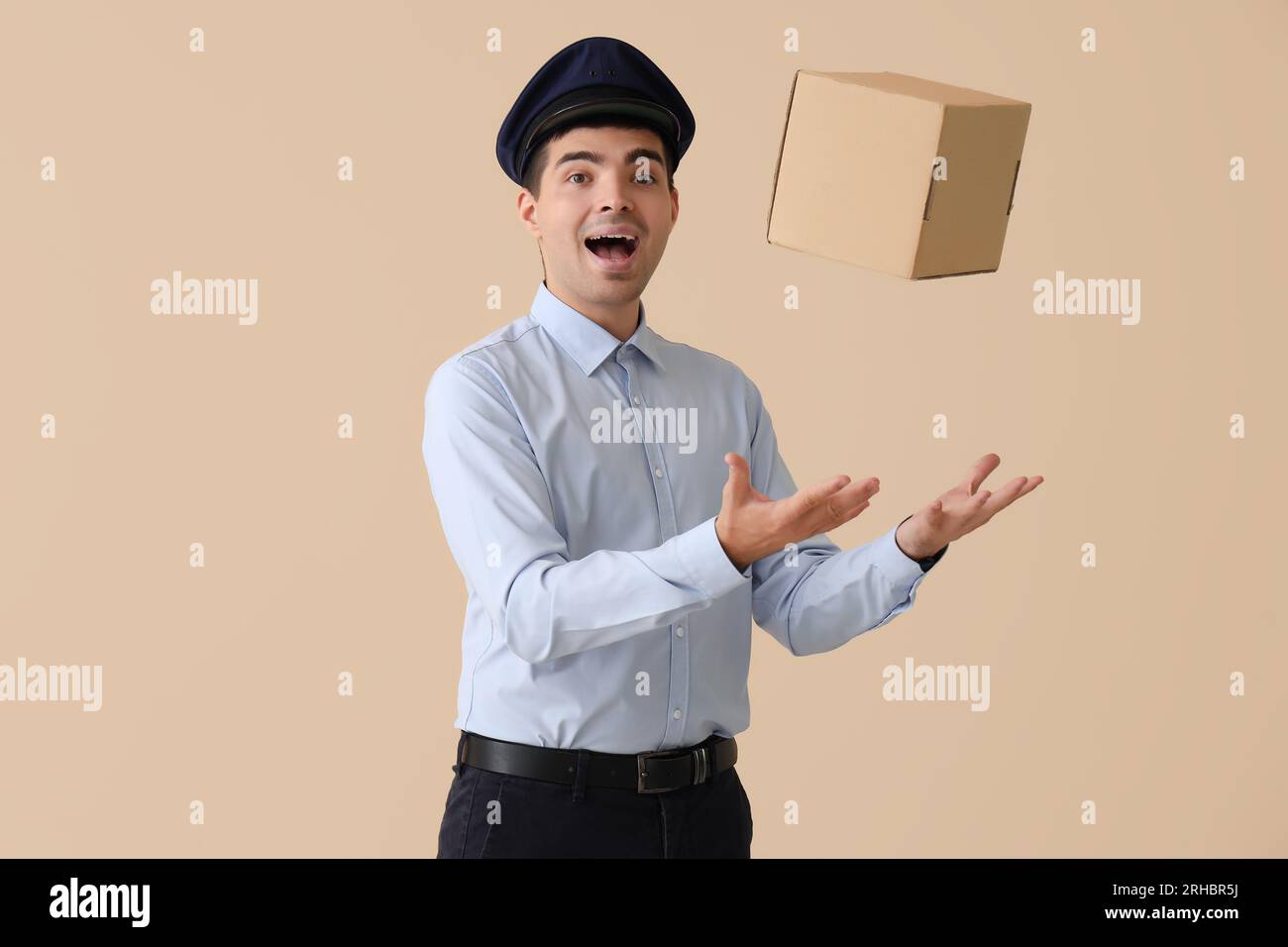 Young postman throwing parcel on beige background Stock Photo - Alamy