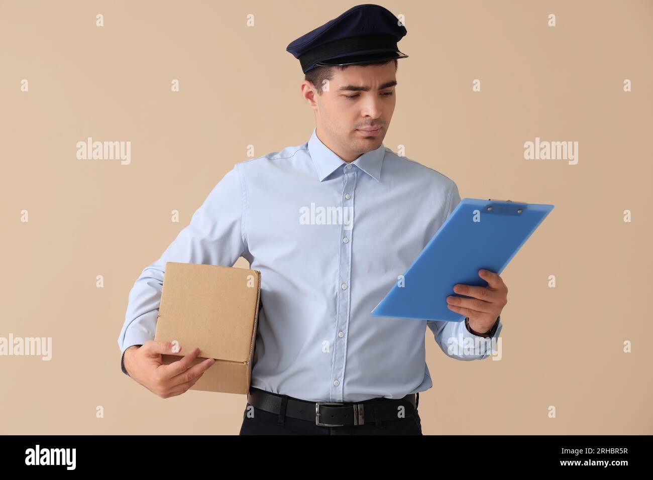 Young postman with parcel and clipboard on beige background Stock Photo ...