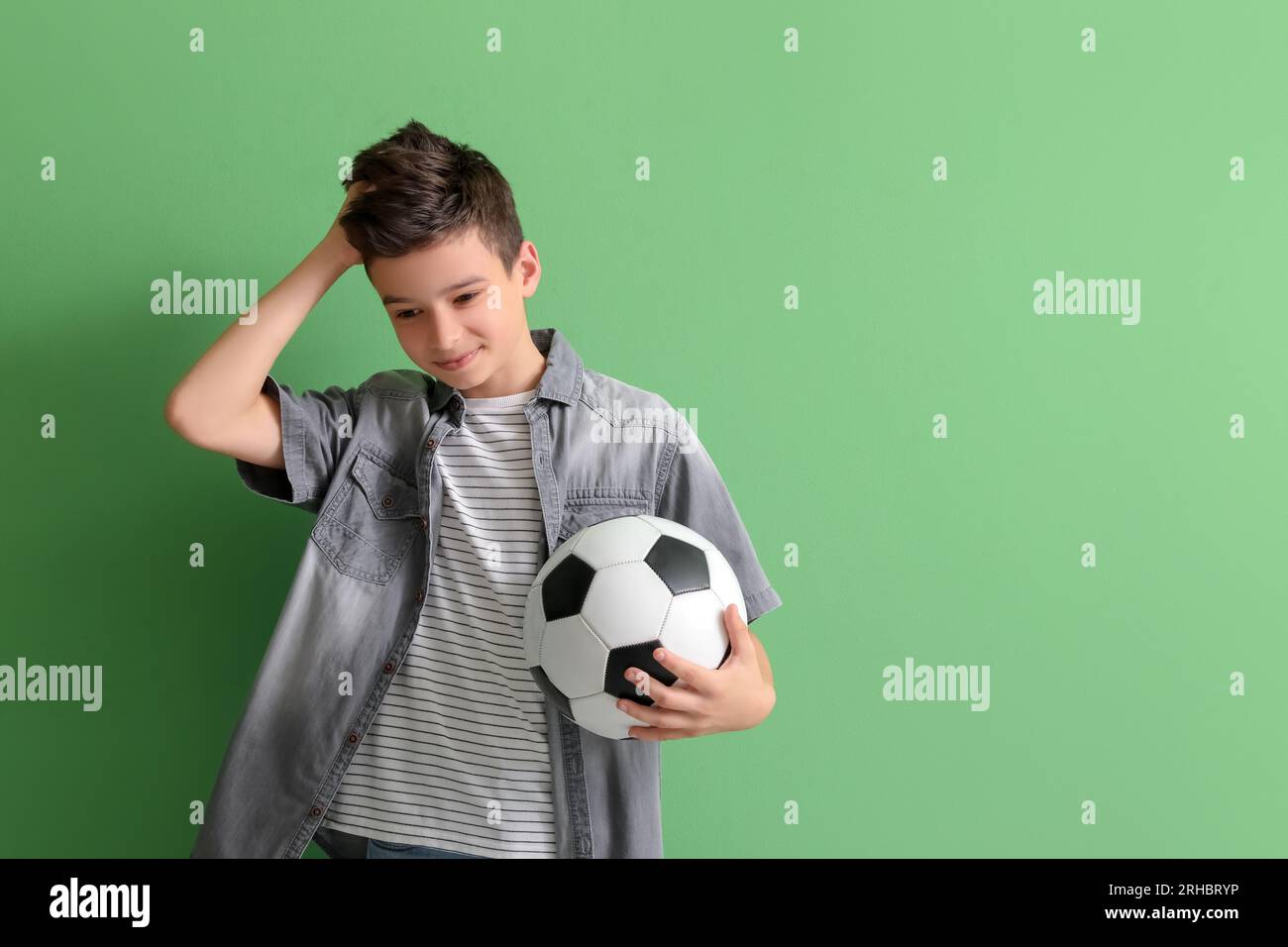 Upset little boy with soccer ball on green background Stock Photo - Alamy