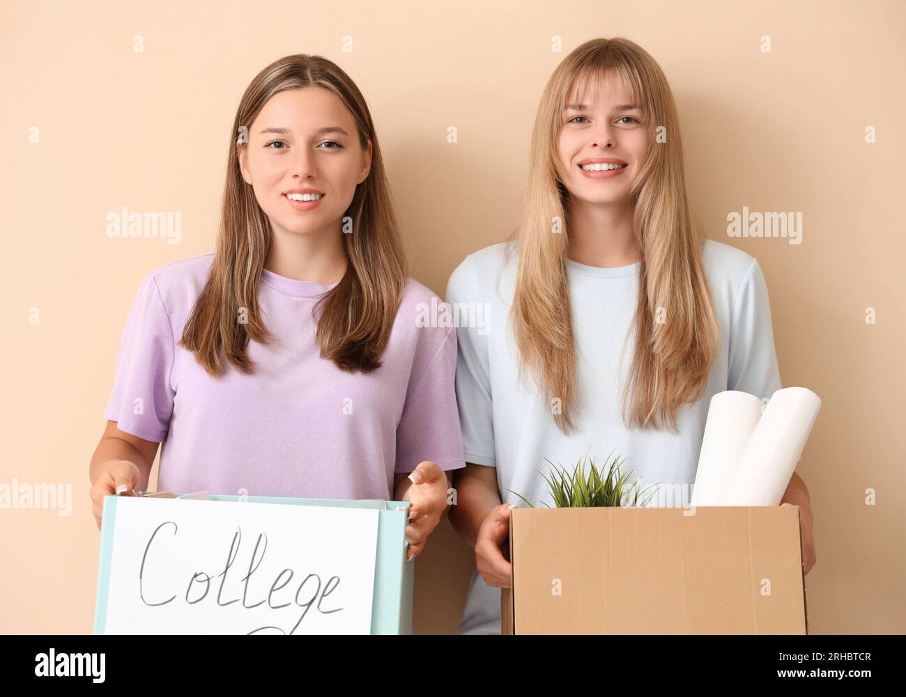 Female students with moving boxes on beige background Stock Photo - Alamy