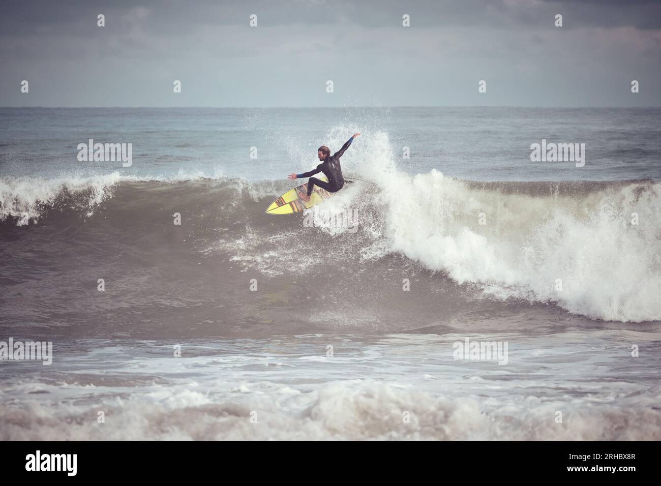 Full body of male surfer standing on surfboard catching wave and riding ...