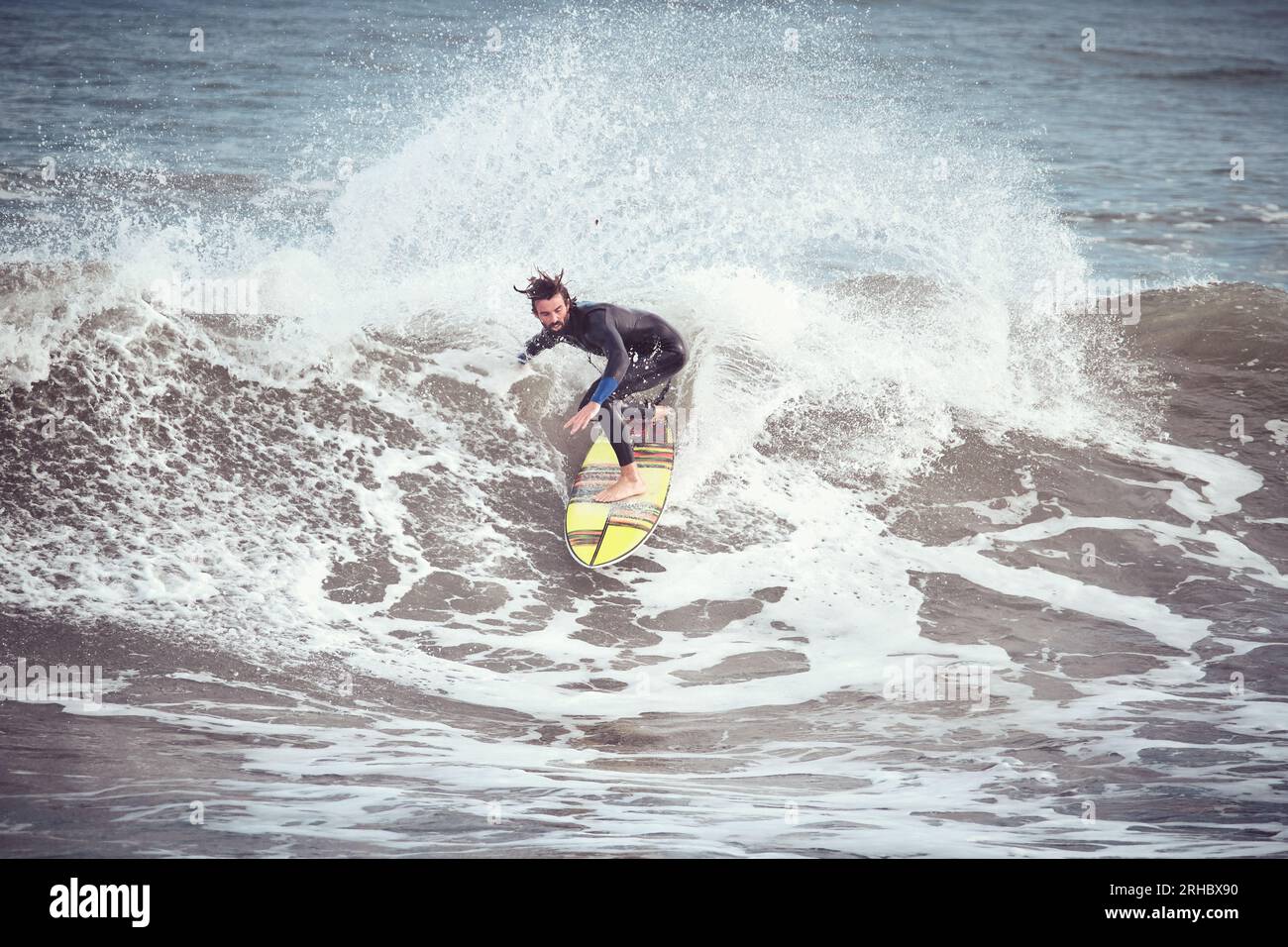 Full body of surfer man in wetsuit standing on surfboard riding foamy ...