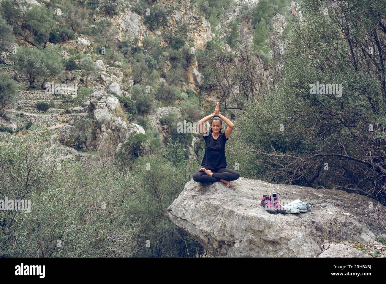 Full body of relaxed young Hispanic female hiker performing Padmasana ...