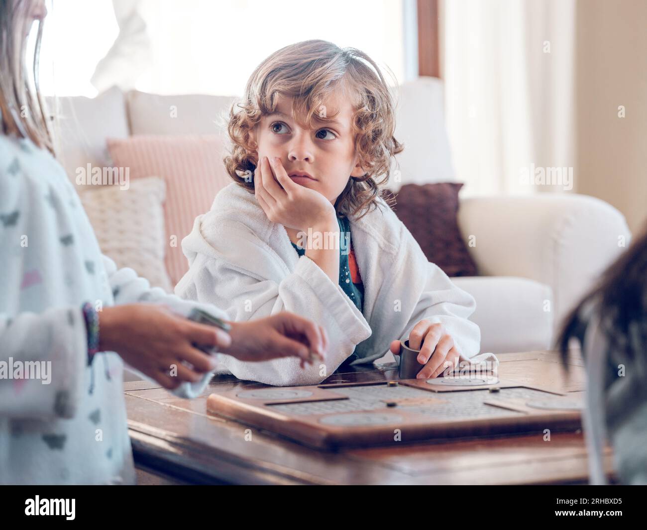 Adorable preteen boy in bathrobe playing board game with little sister ...