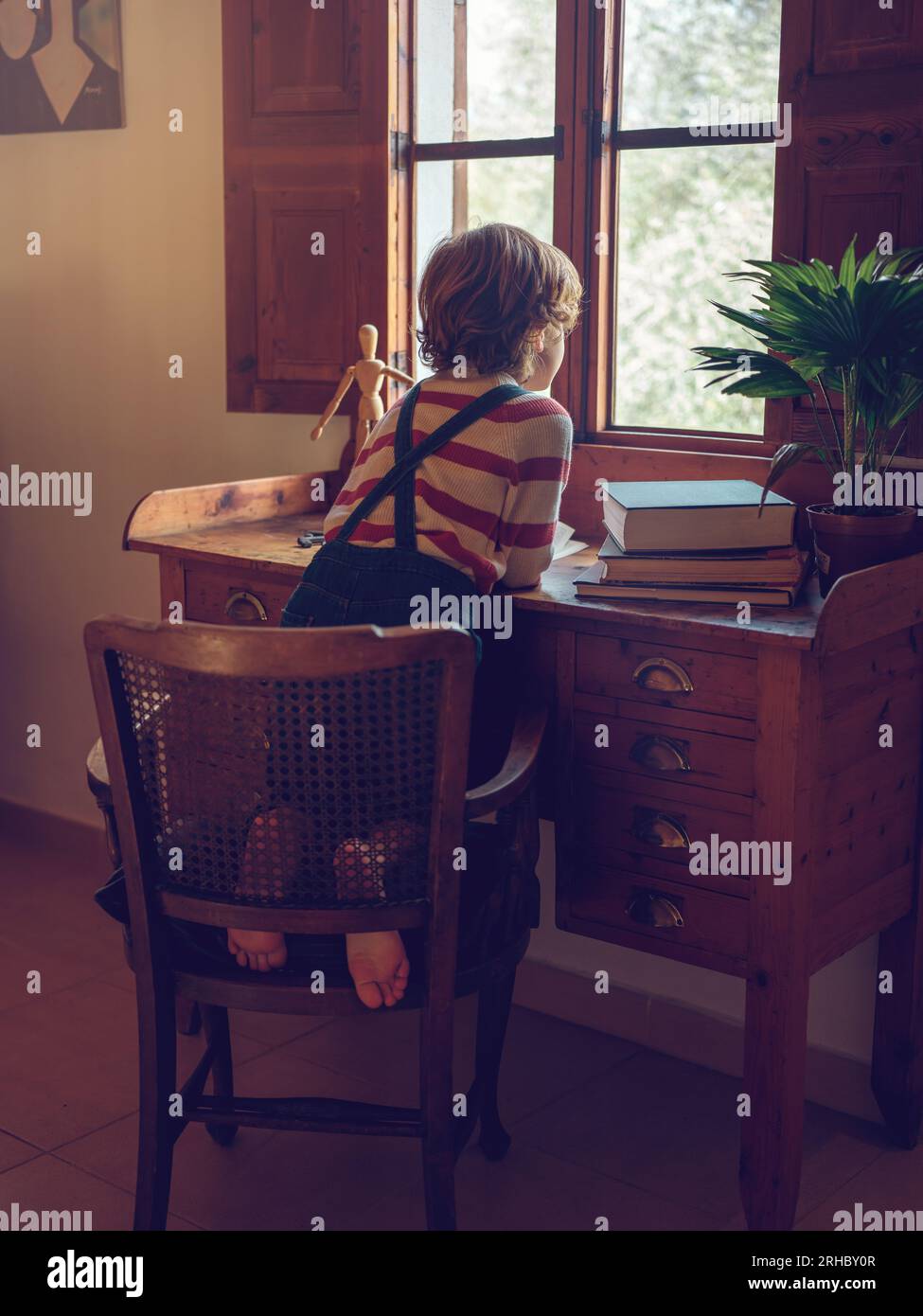 Back view of barefoot anonymous child climbing into chair and looking ...