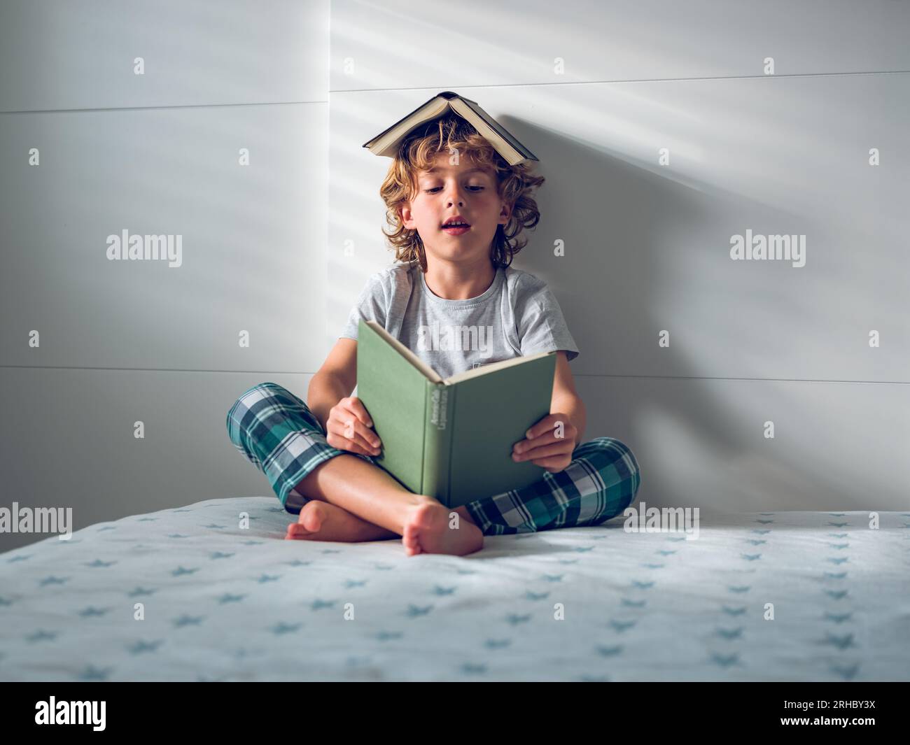 Full body of barefoot little schoolboy sitting with crossed legs on ...