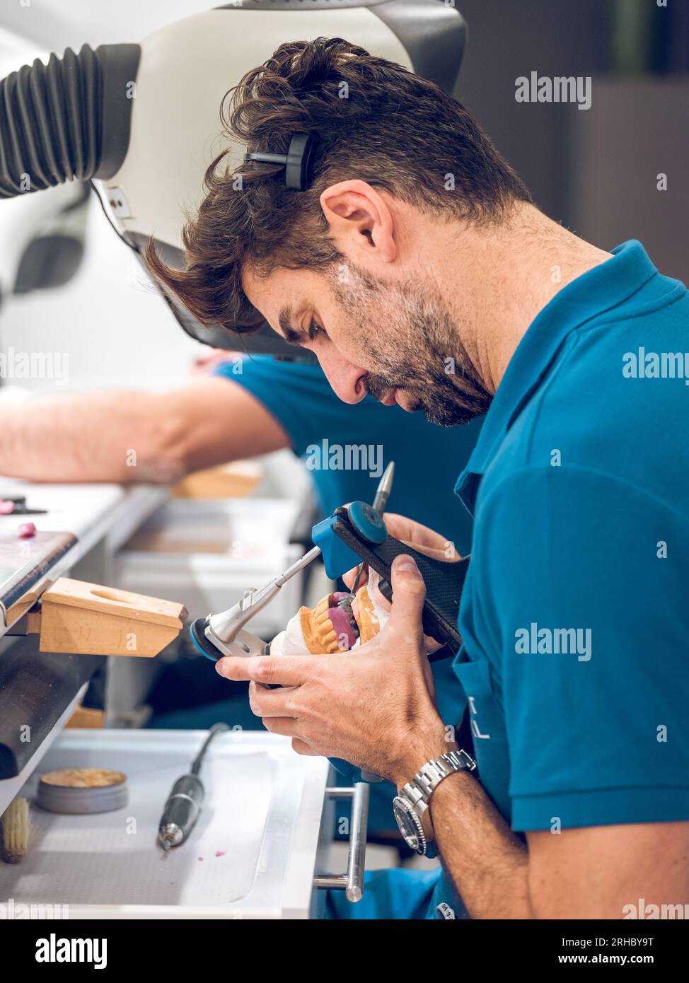 Side view of bearded male orthodontist technician using tool while ...
