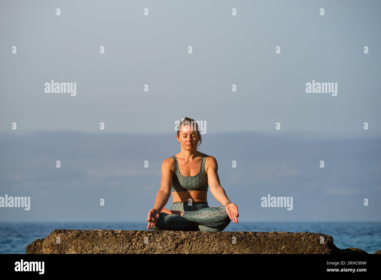 Full body of young female athlete in activewear taking Padmasana pose ...