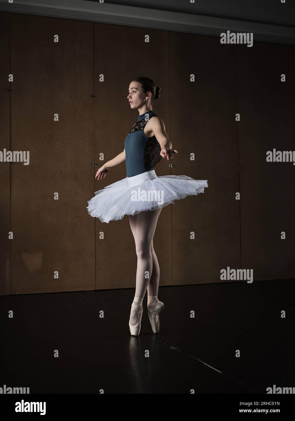 Side view of full body slender ballerina in tutu balancing on tiptoes ...