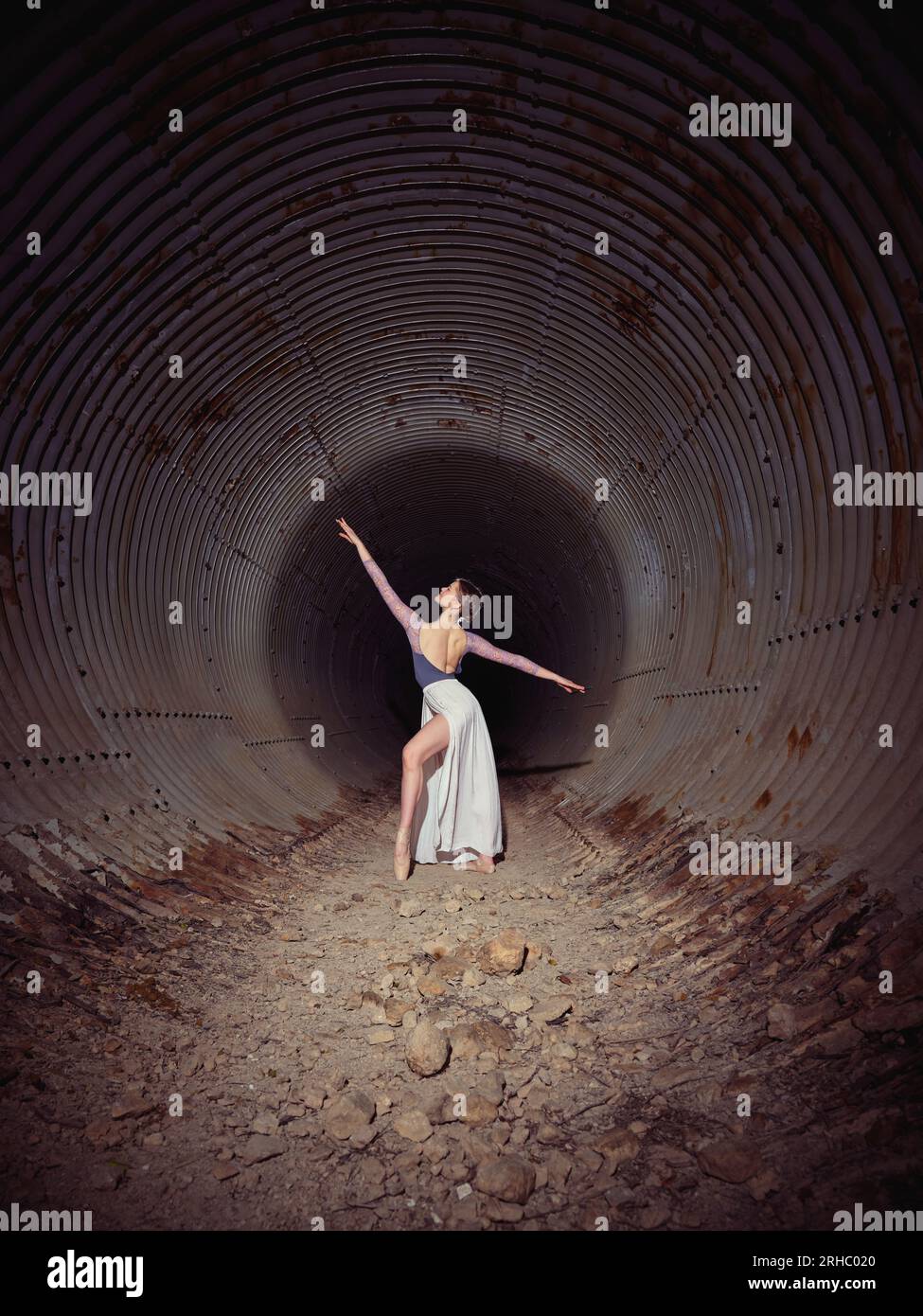 Full body side view of slim female ballet dancer looking at raised arm ...
