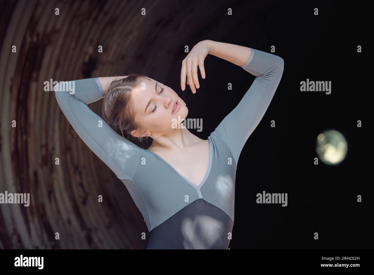 Charming talented female ballet dancer with raised arms and closed eyes ...