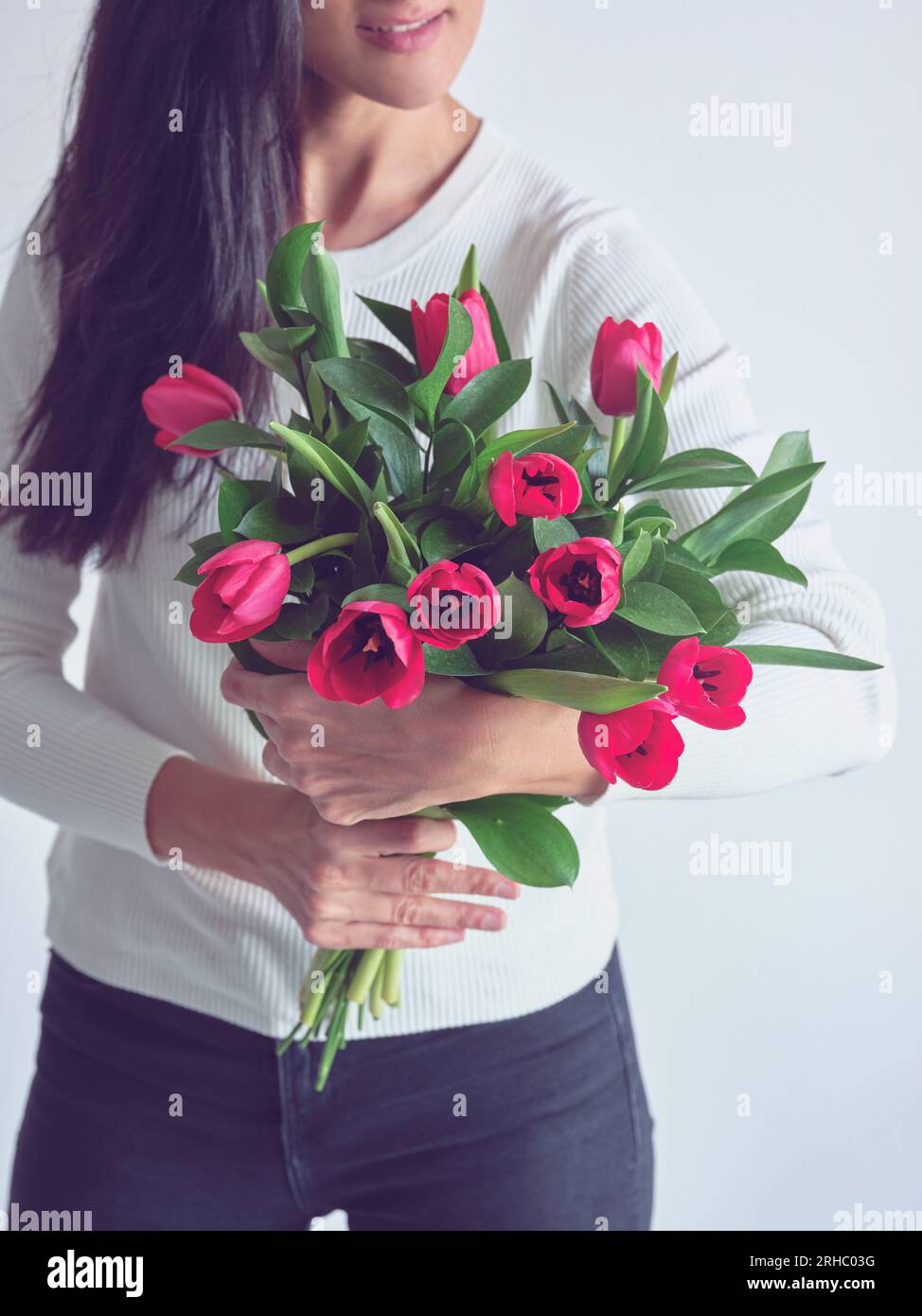 Crop anonymous lady touching and sniffing bunch of bright tulips with ...