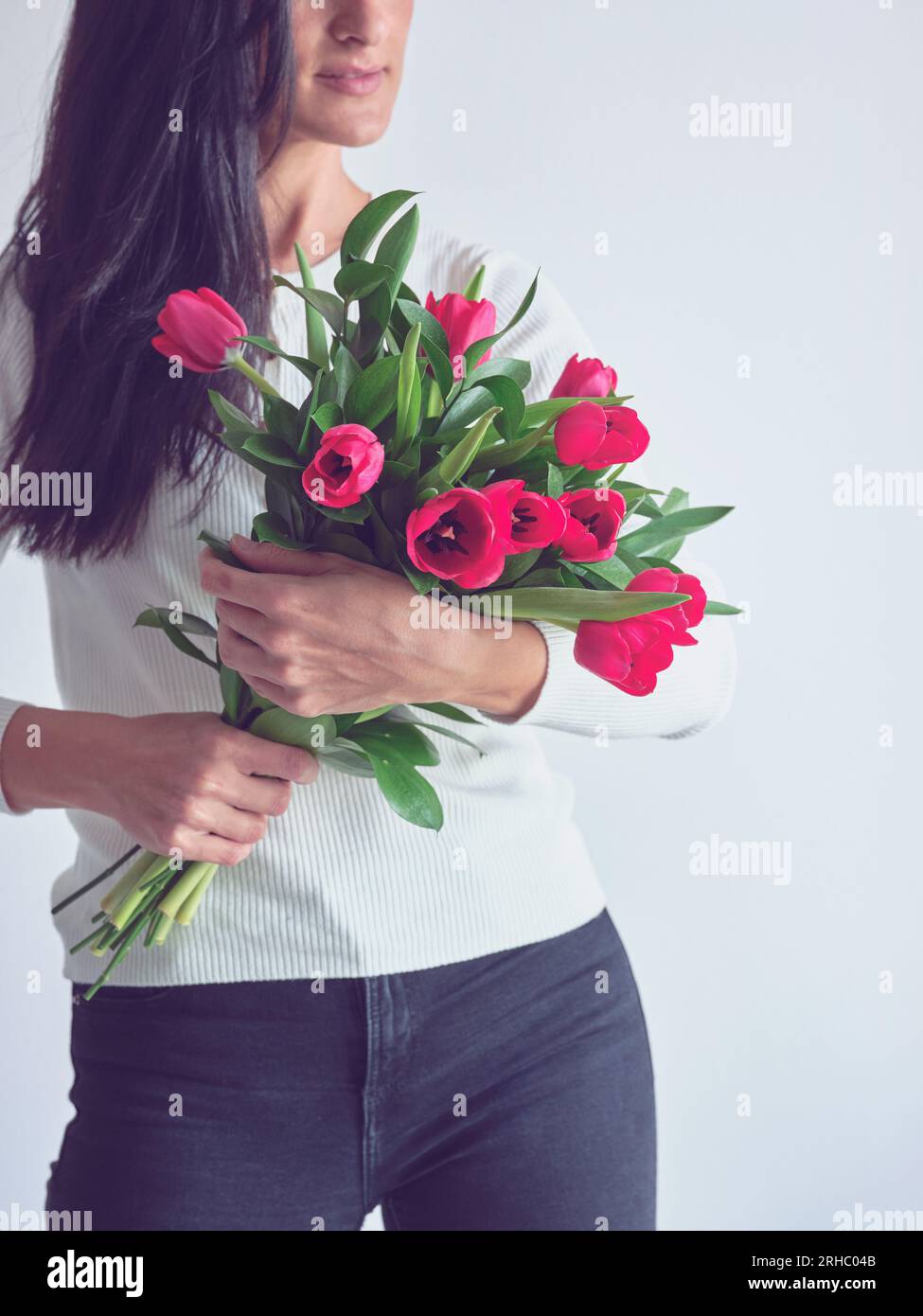 Crop anonymous lady touching and sniffing bunch of bright tulips with ...