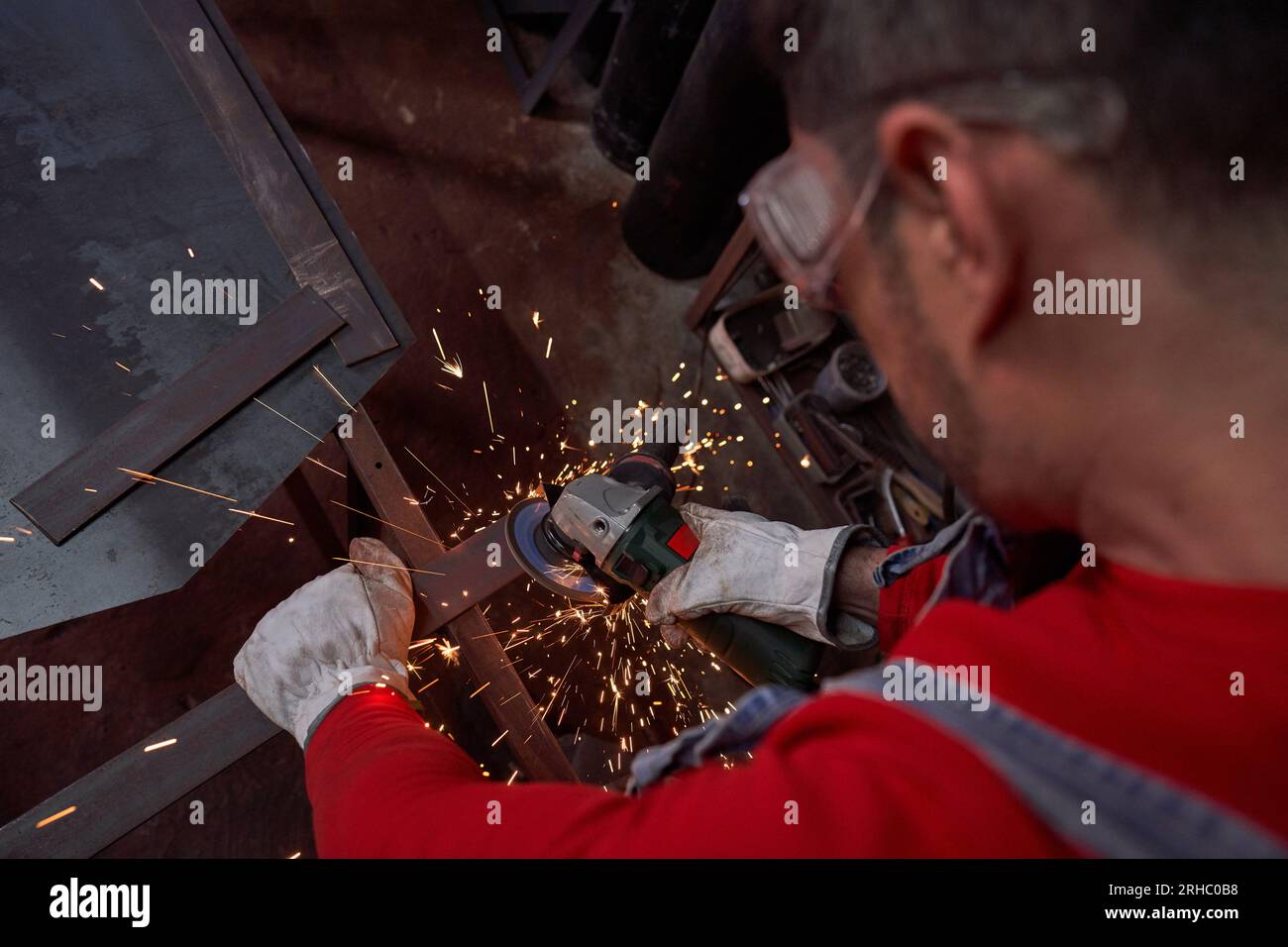Man in plastic protective glasses holding grinder and cutting part of ...