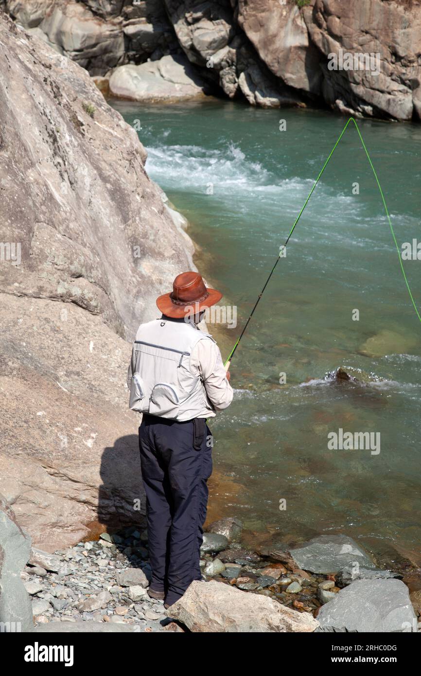 Rear view of a man standing on riverbank trout fishing, India Stock ...