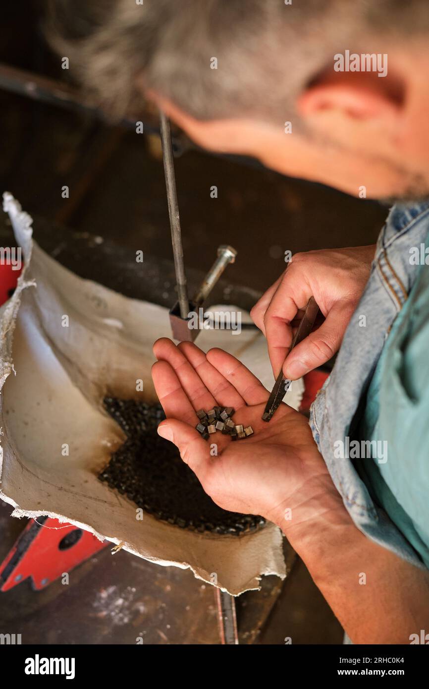 High angle of crop anonymous male worker putting little metal pieces ...