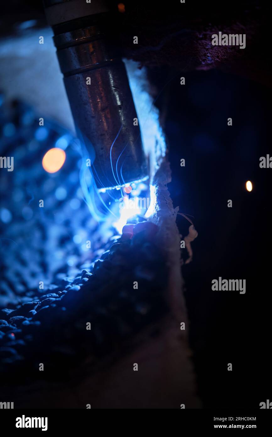 Welding machine emitting beam of blue light and smoke while joining ...