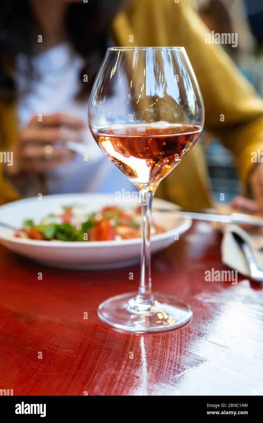 Woman sitting at a table eating salad and drinking rose wine Stock ...