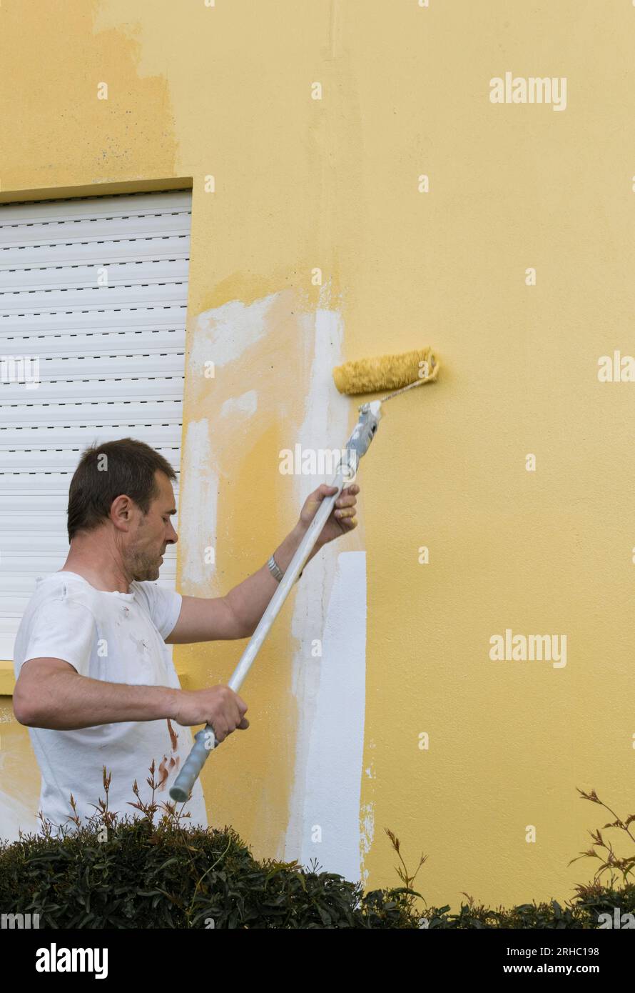 Rear view of a man painting a house yellow, Spain Stock Photo - Alamy