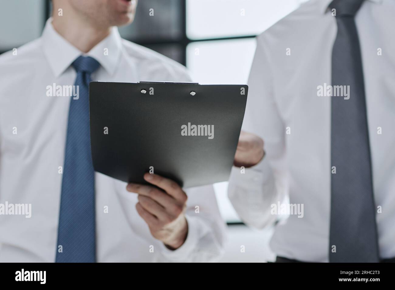 Businesspeople in suits holding a black document folder and pondering ...