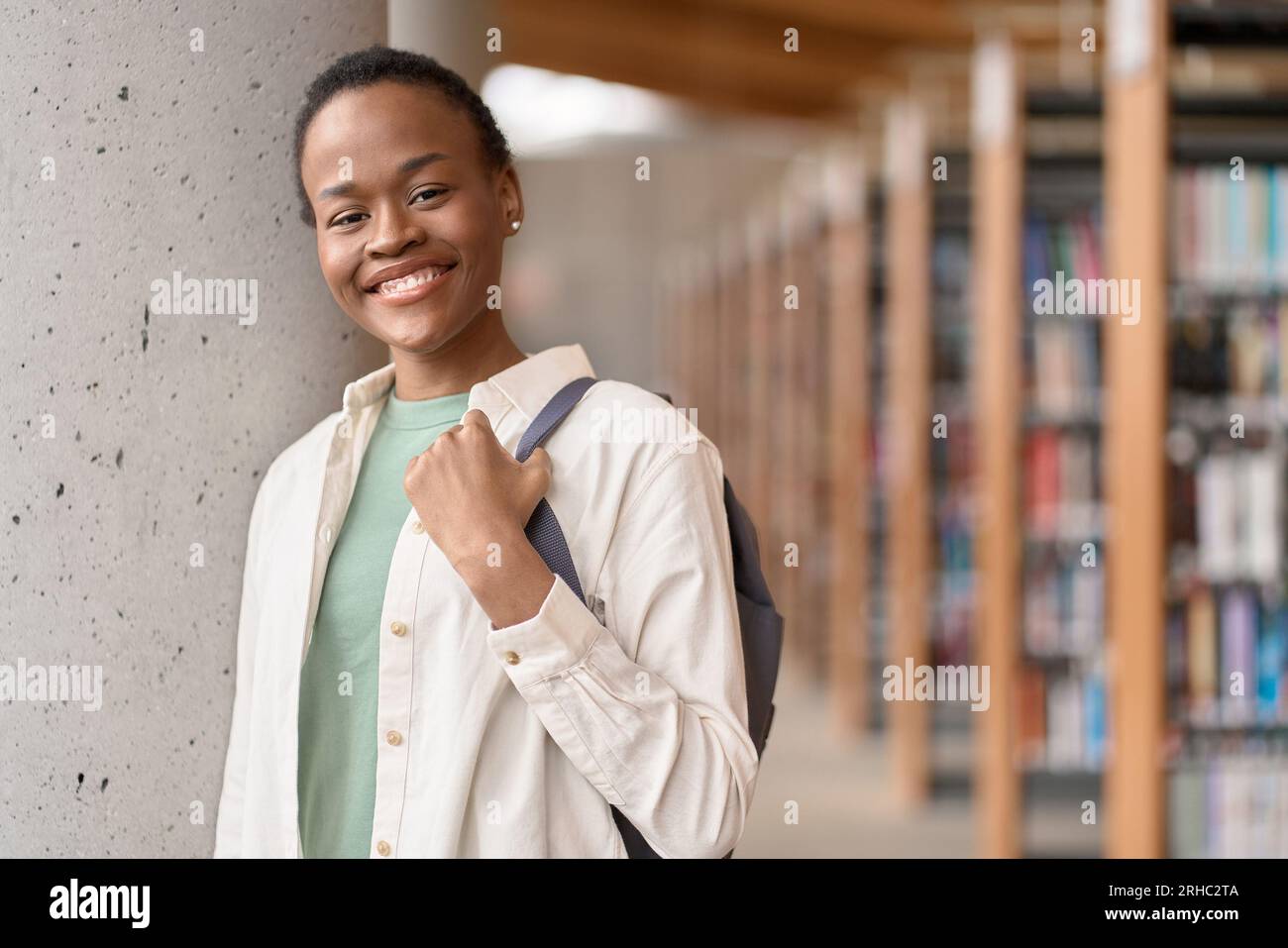 Happy African girl student holding backpack standing in library, portrait Stock Photo - Alamy
