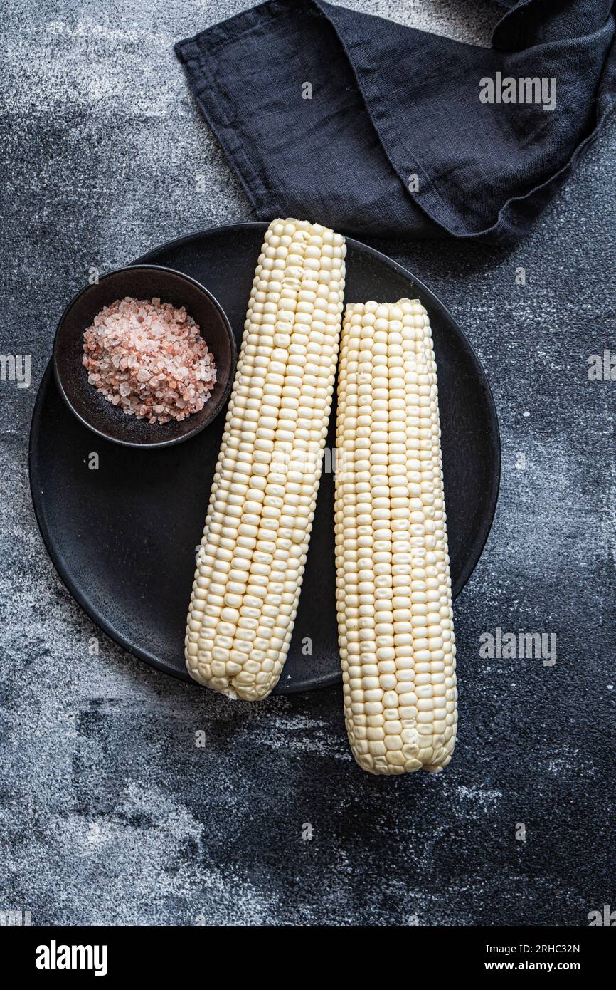 Overhead view of two corn cobs with pink Himalayan salt on a plate ...