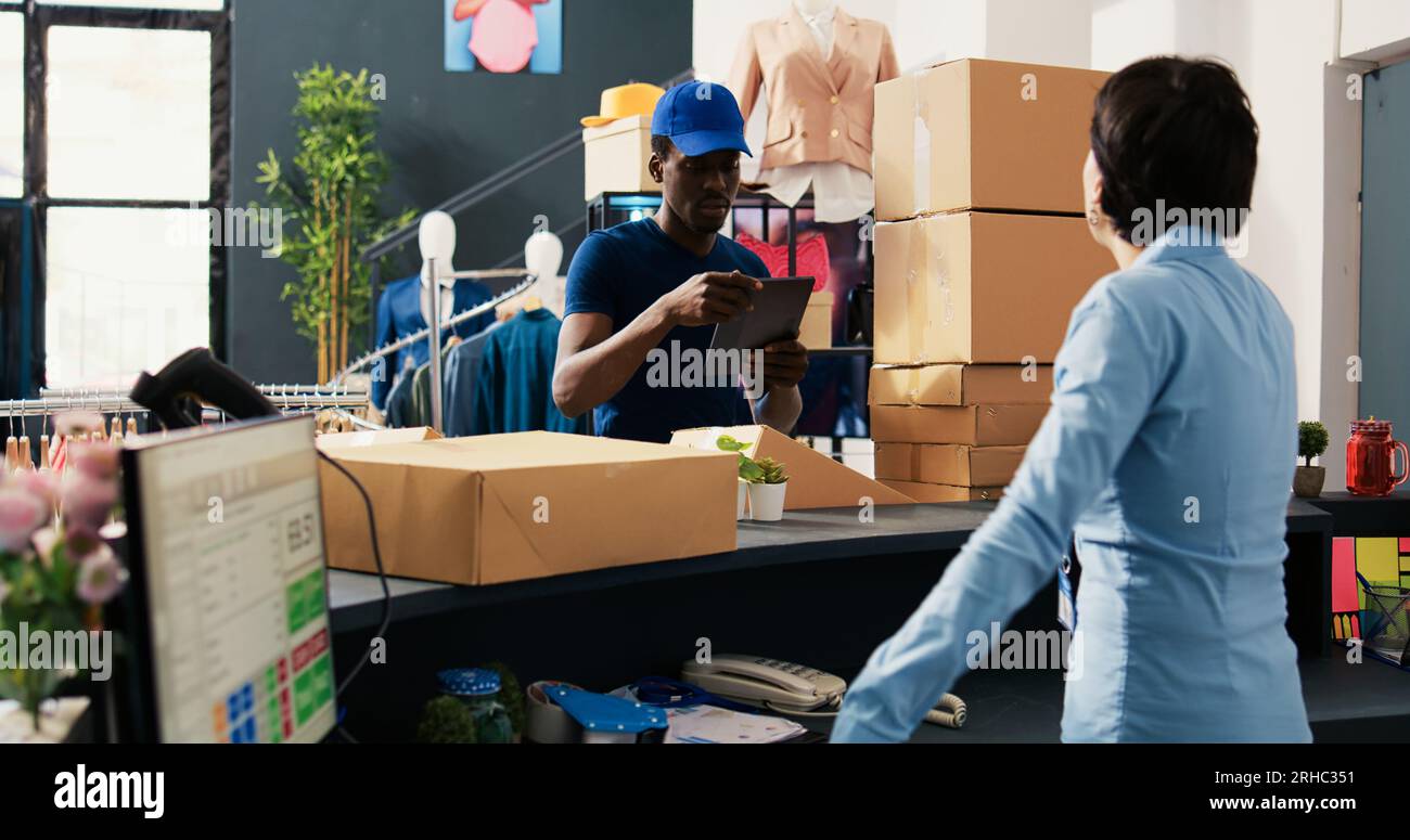 African american courier taking photo of carton boxes using tablet ...