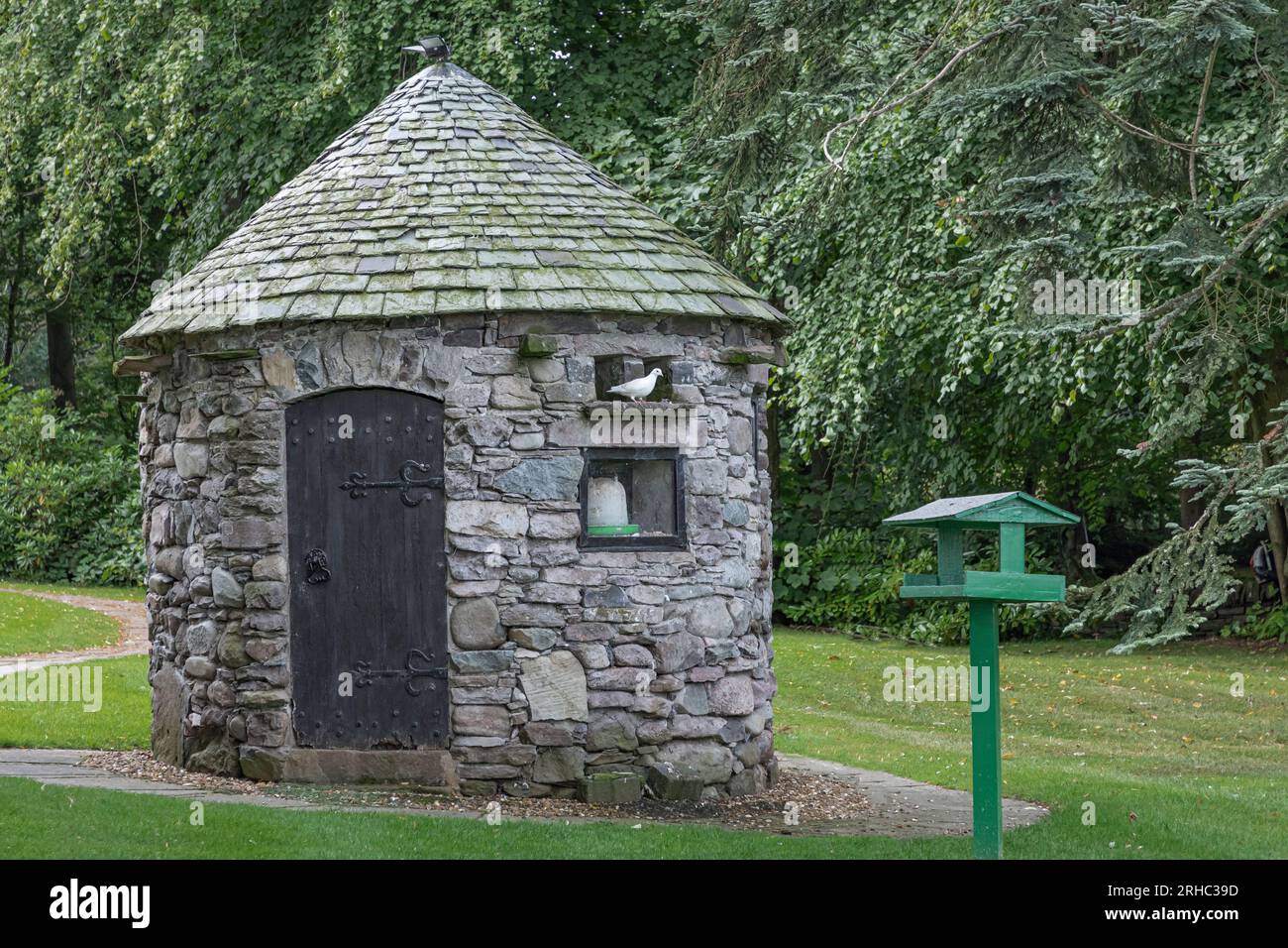 Round stone dovecot with a black door and a white dove leaving via a ...