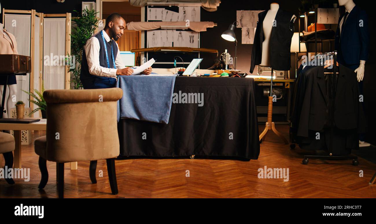 Male tailor checking sketches in atelier, using outline drawings of ...