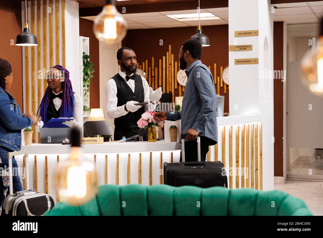 African American hotel receptionist talking with guest, confirming ...