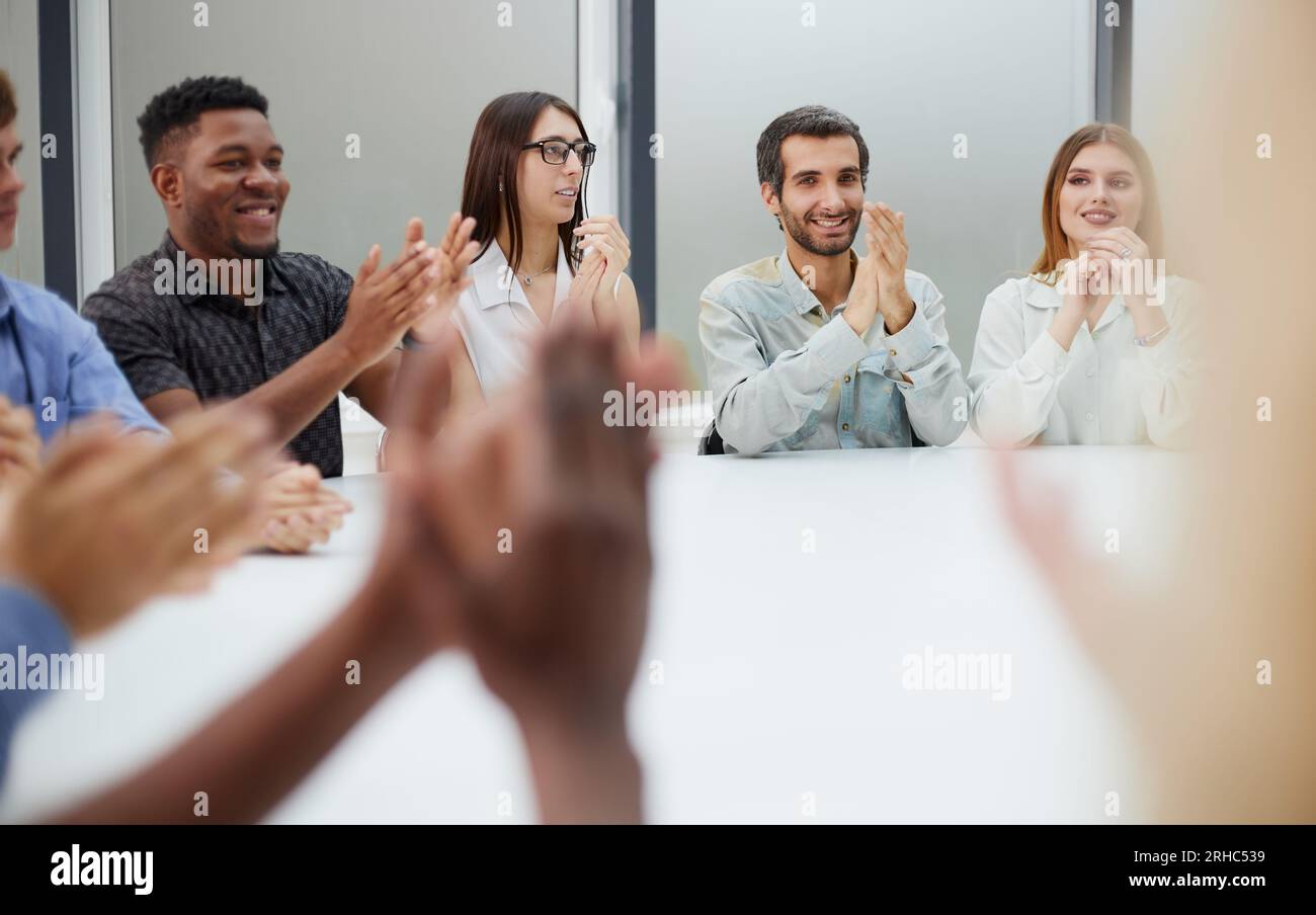 Group of young business workers smiling and clapping to partner at the ...