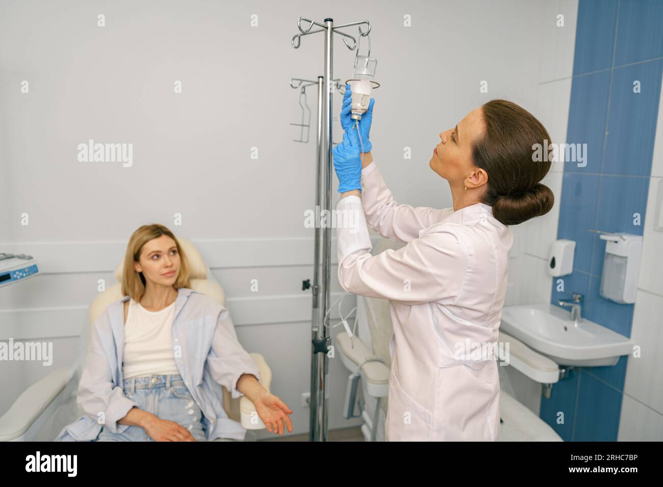 Professional doctor putting an IV drip to female patient intravenously ...