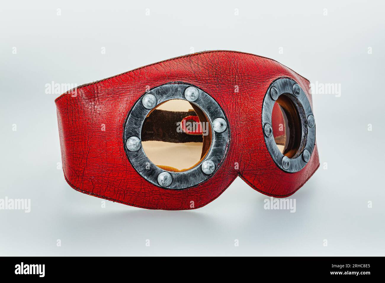 Close-up of a red steampunk leather mask with riveted round goggles on ...