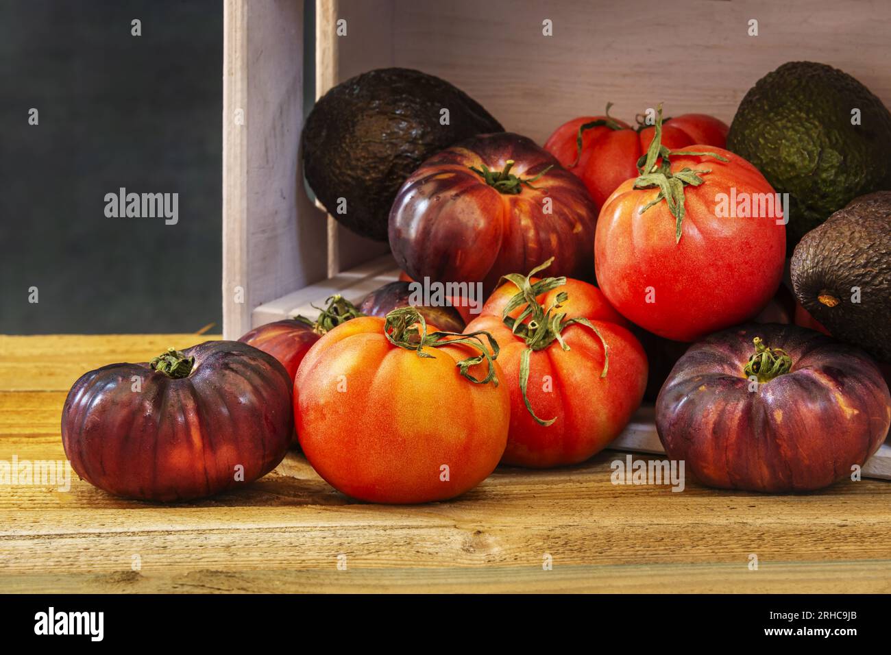 An overturned wooden crate on an unvarnished wooden table full of ripe ...