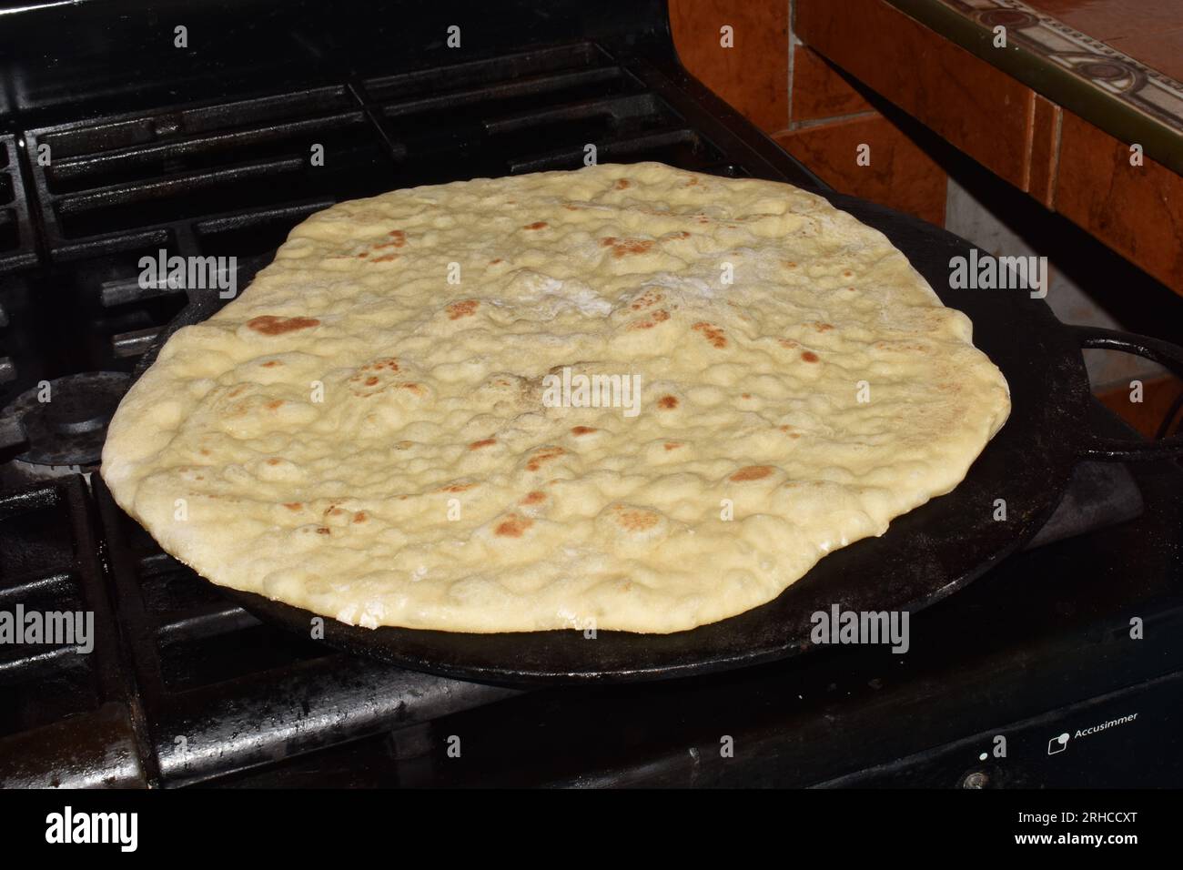 Sada roti being cooked on a tawa, a kitchen utensil which is made from ...