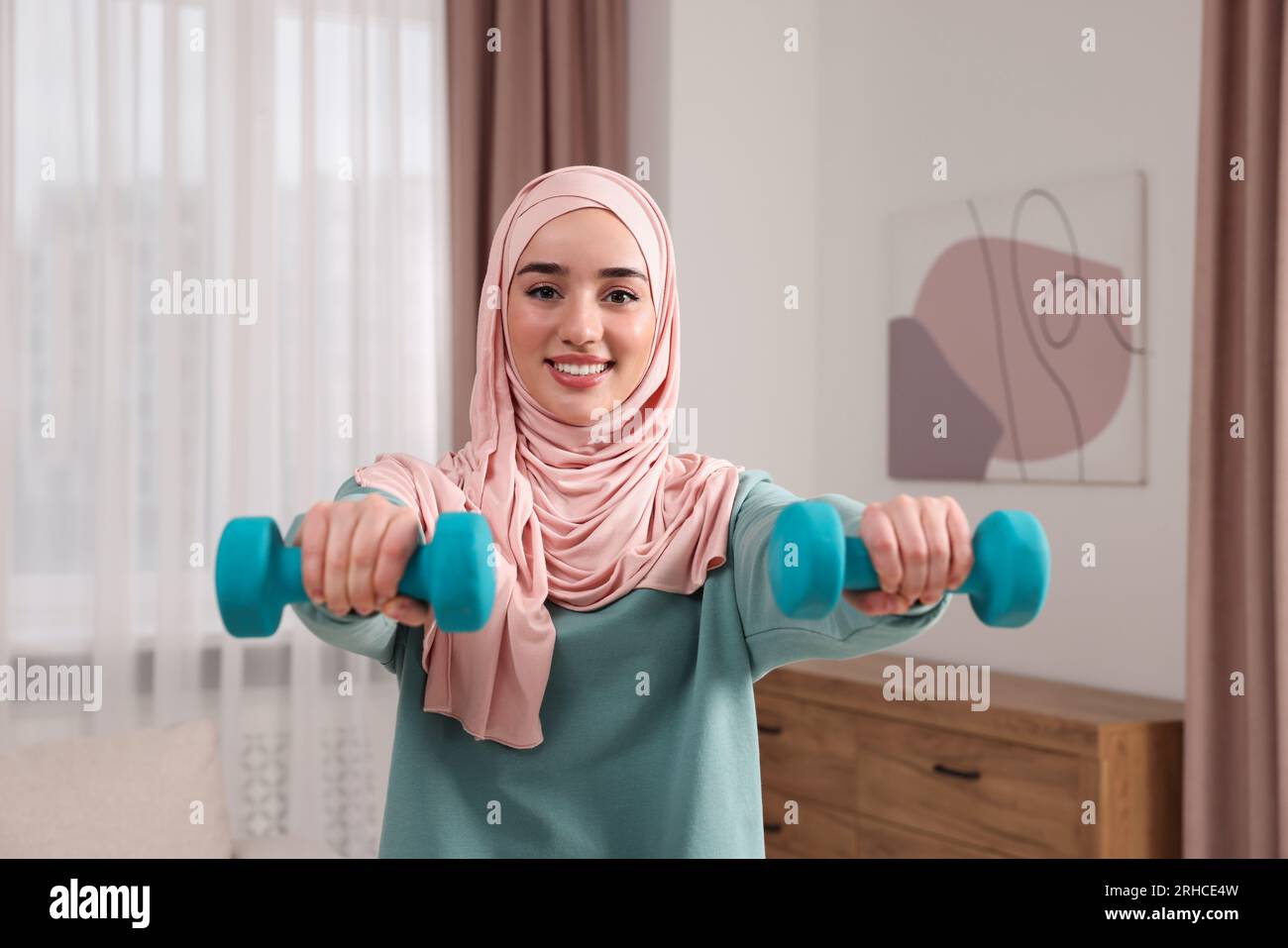 Muslim woman in hijab doing exercise with dumbbells at home Stock Photo - Alamy