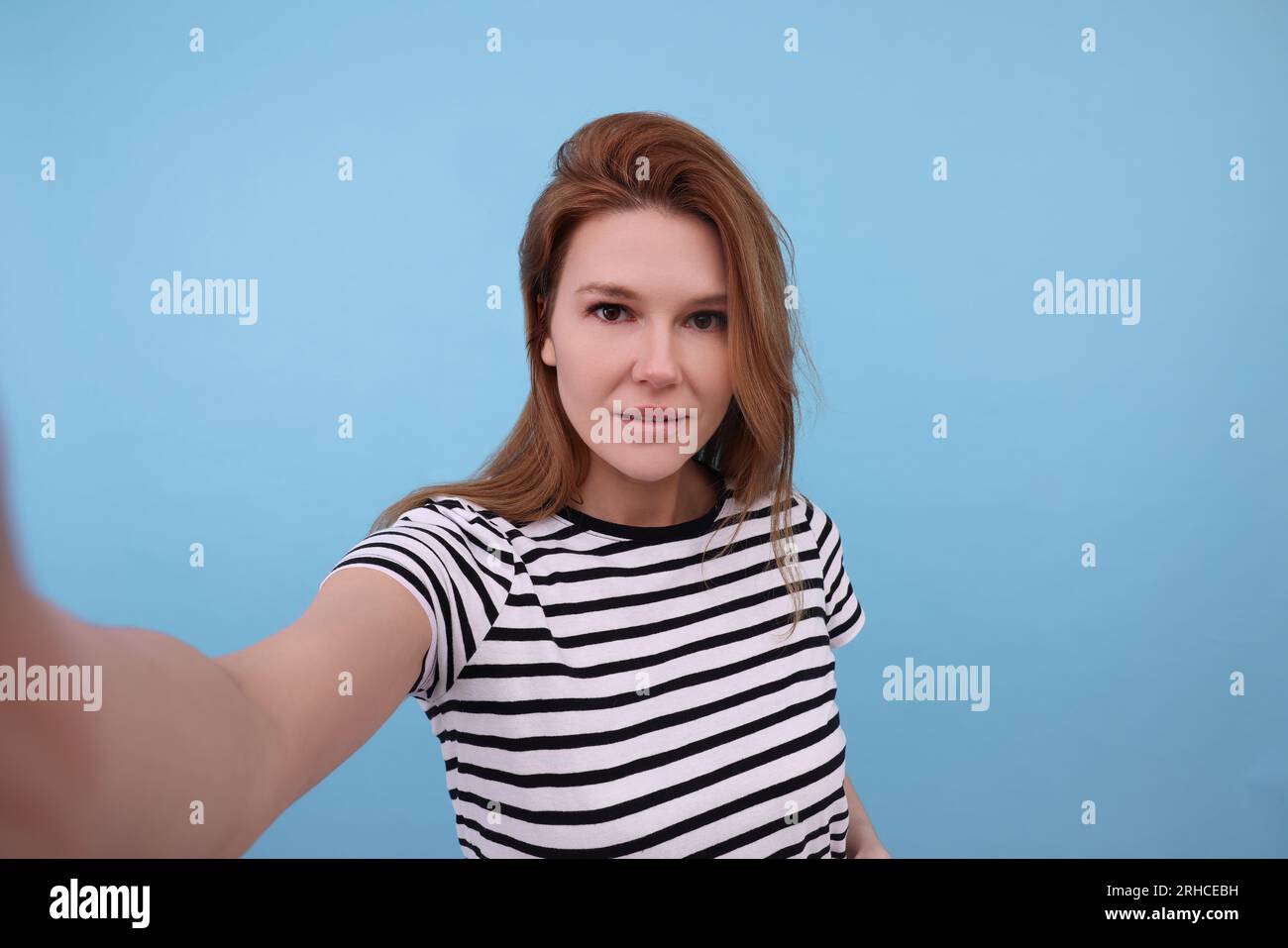 Beautiful woman taking selfie on light blue background Stock Photo - Alamy