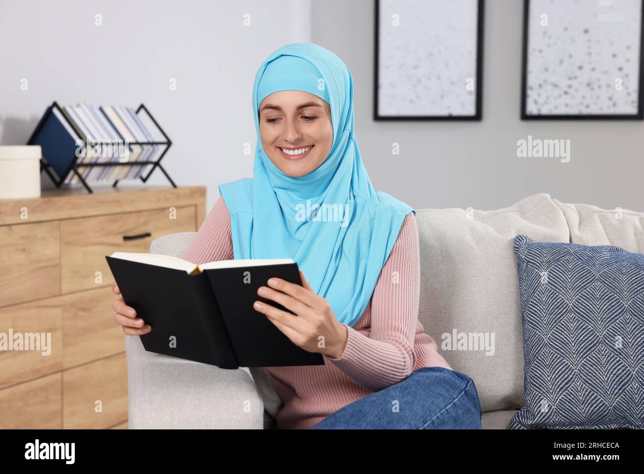 Muslim woman reading book on couch in room Stock Photo - Alamy
