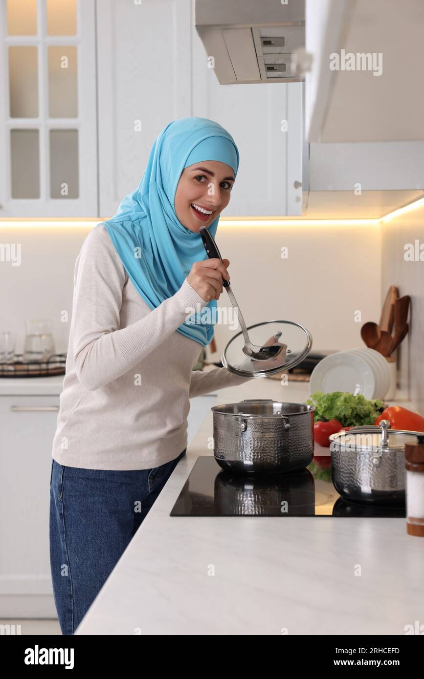 Muslim woman cooking dish in saucepan on cooktop indoors Stock Photo ...